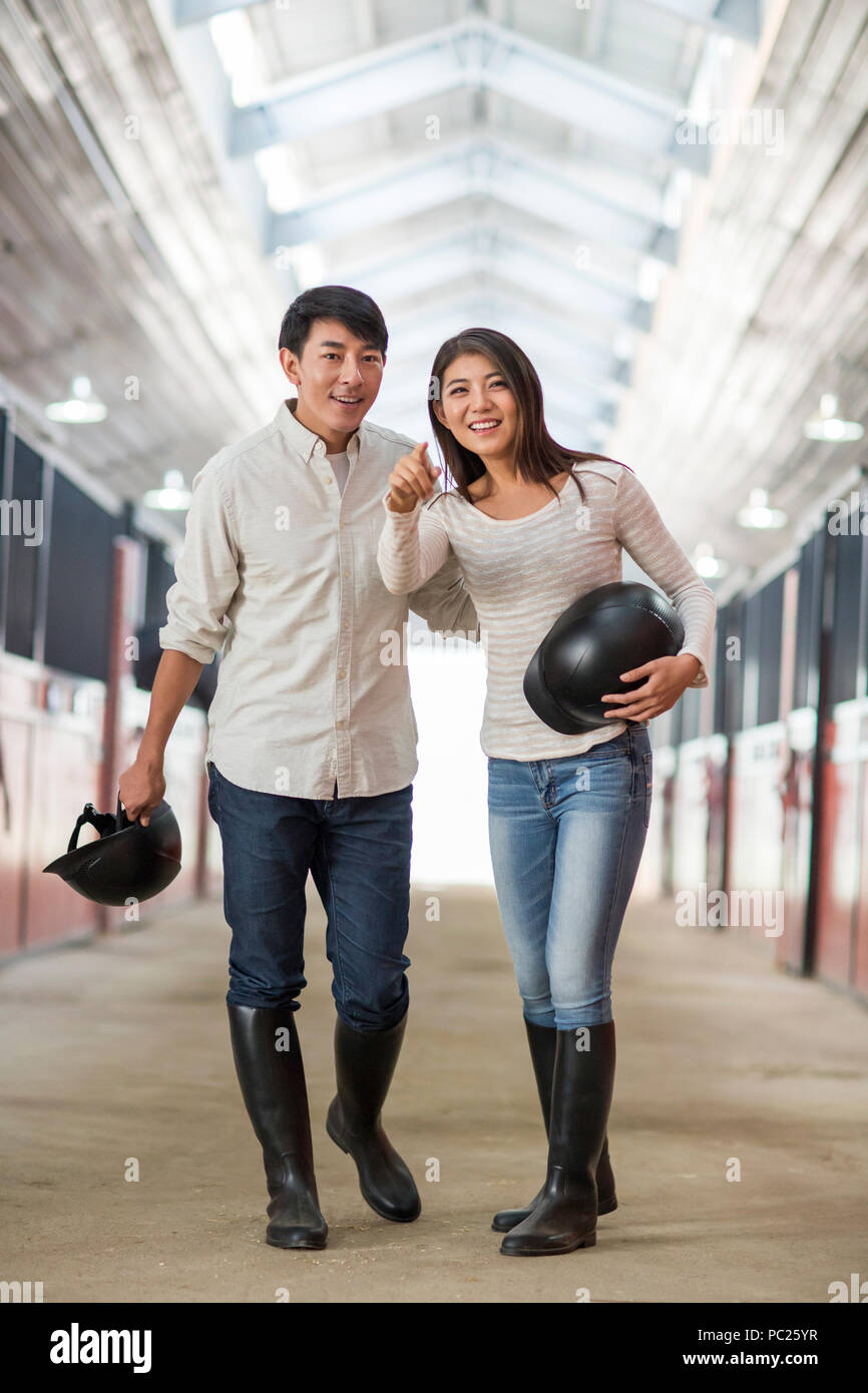 Cheerful young Chinese couple in horse stable Stock Photo - Alamy