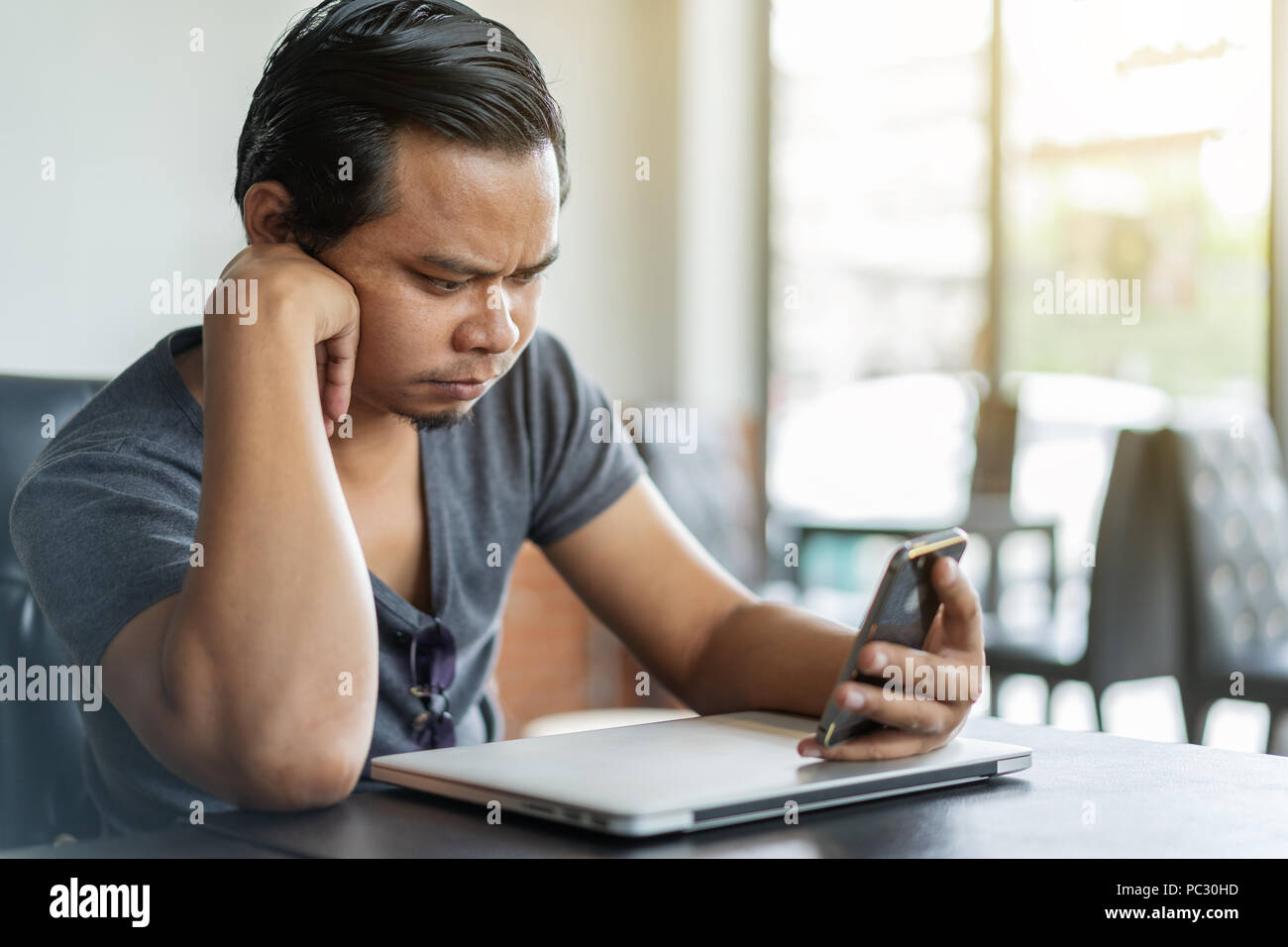 young man stressed using smartphone in a cafe Stock Photo - Alamy