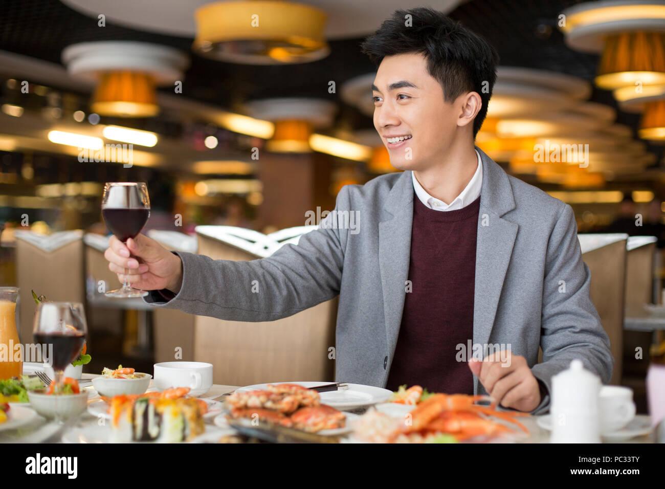 Cheerful young Chinese man having buffet dinner Stock Photo - Alamy