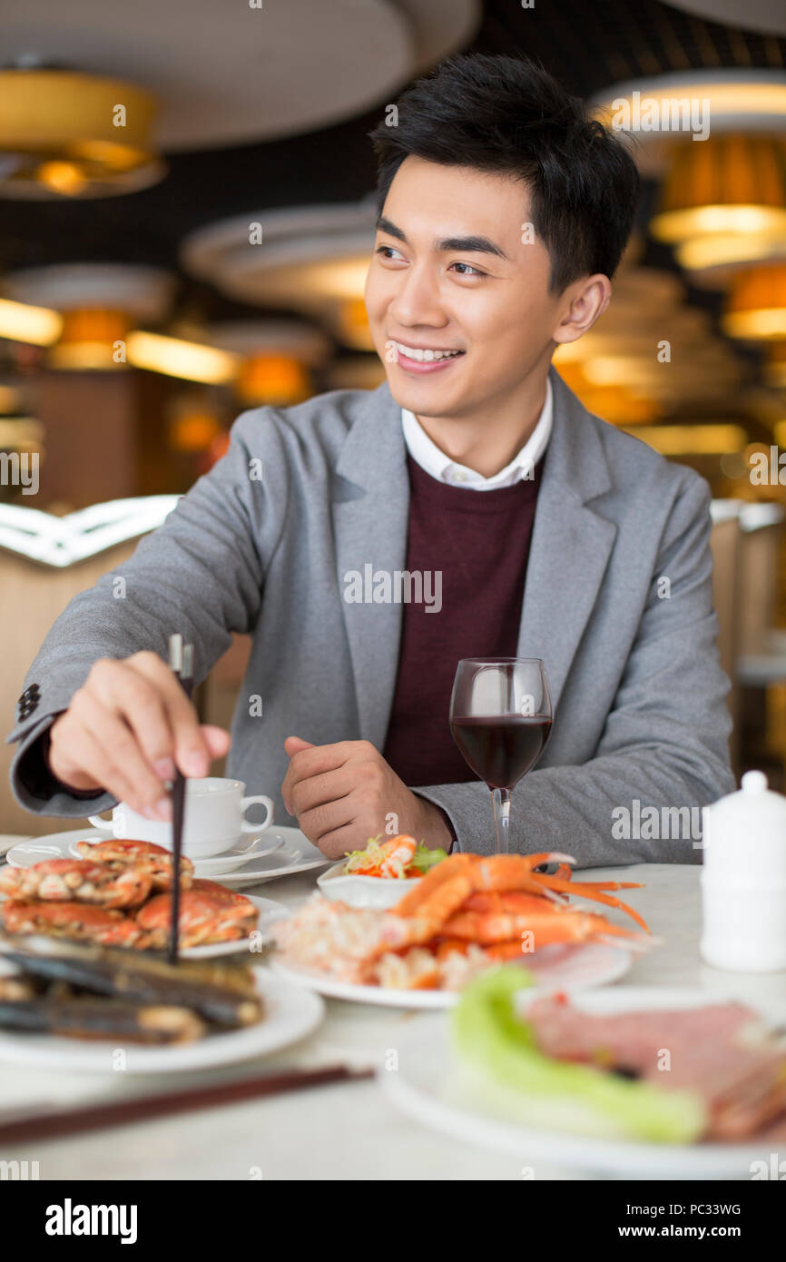 Cheerful young Chinese man having buffet dinner Stock Photo - Alamy