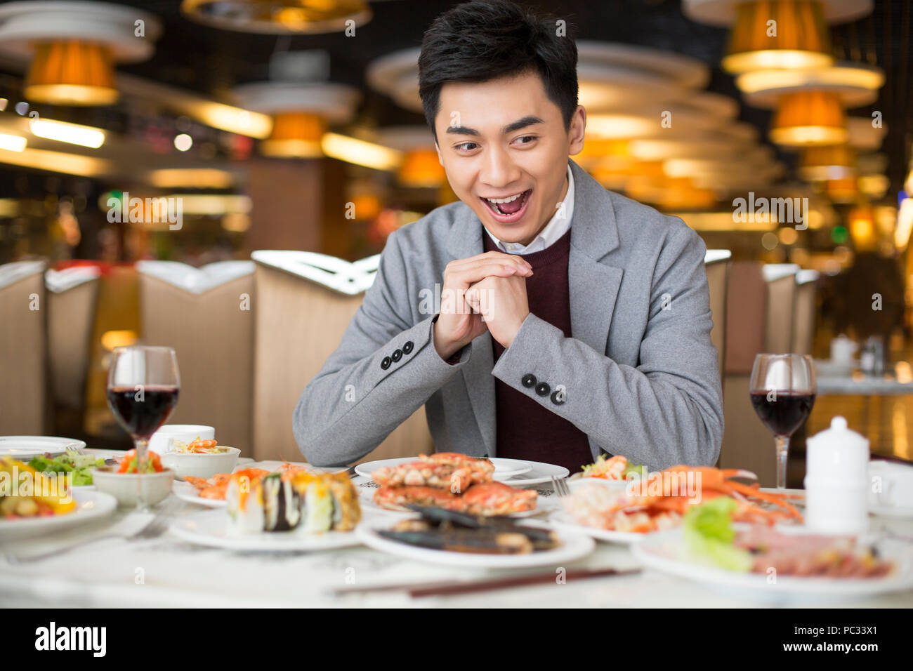 Cheerful young Chinese man having buffet dinner Stock Photo - Alamy