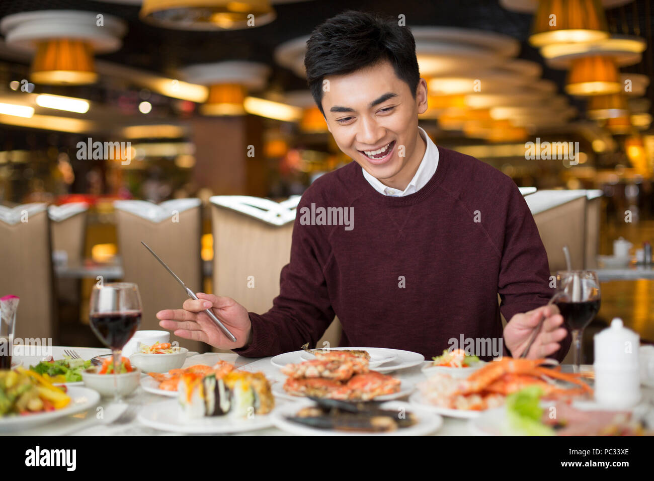 Cheerful young Chinese man having buffet dinner Stock Photo - Alamy