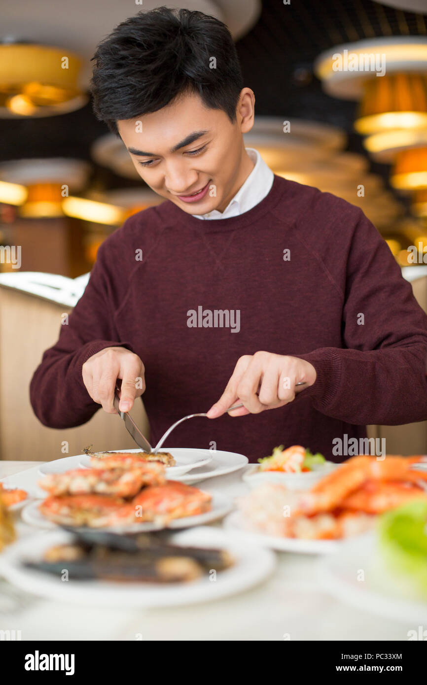 Cheerful young Chinese man having buffet dinner Stock Photo - Alamy