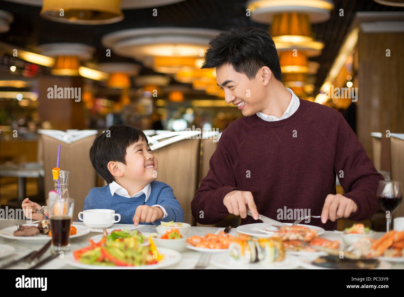 Cheerful Chinese father and son having buffet dinner Stock Photo - Alamy