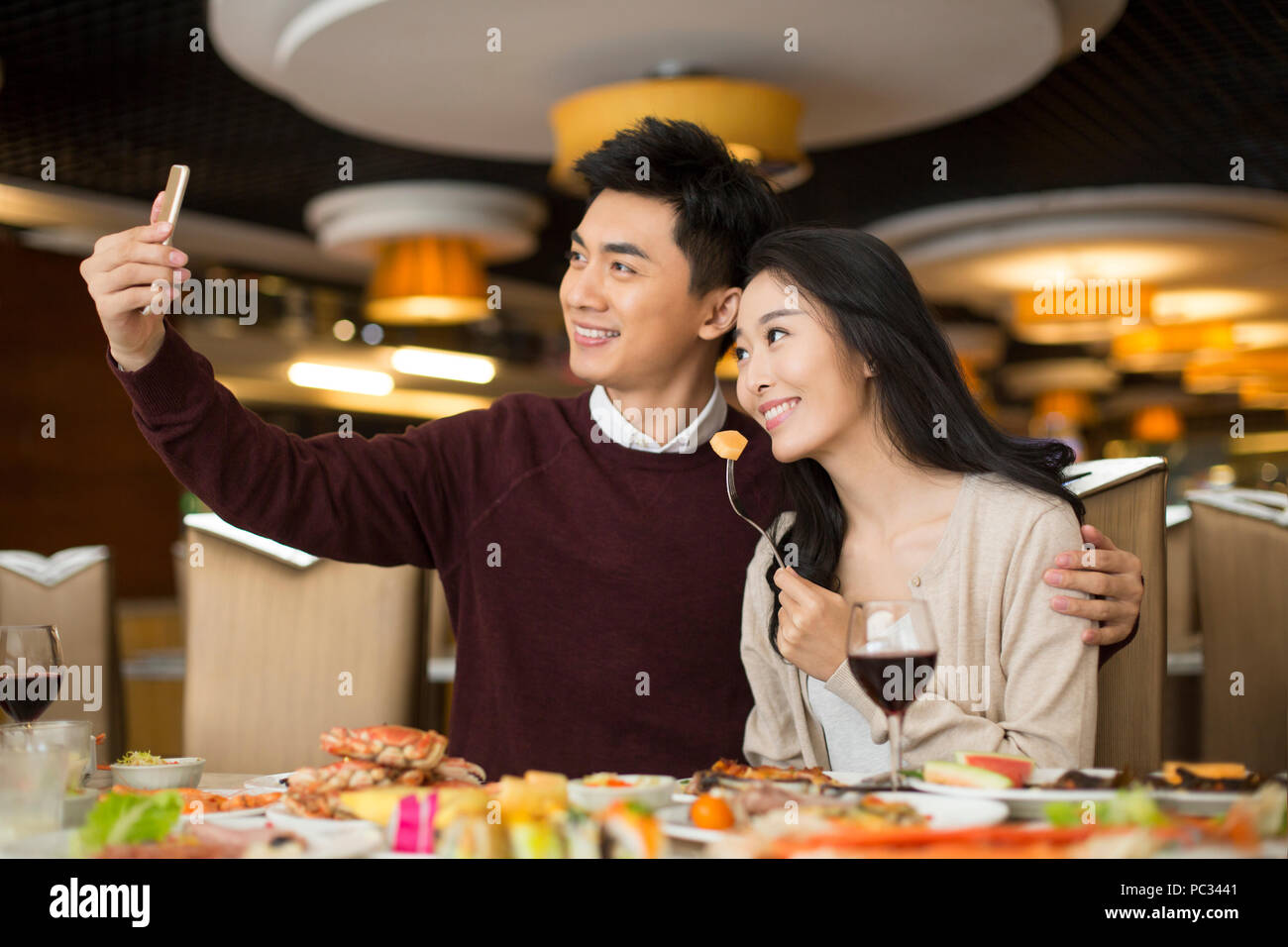 Cheerful young Chinese couple having buffet dinner Stock Photo - Alamy