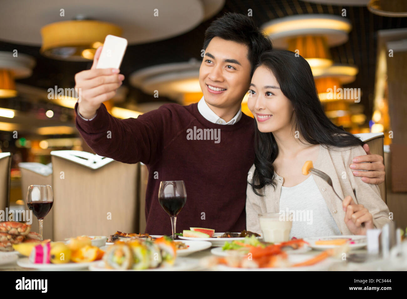Cheerful young Chinese couple having buffet dinner Stock Photo - Alamy