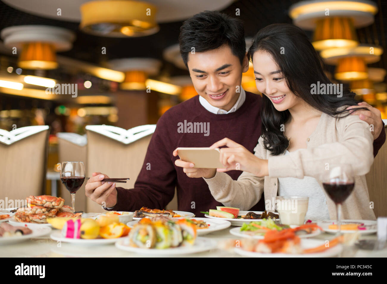 Cheerful young Chinese couple having buffet dinner Stock Photo - Alamy