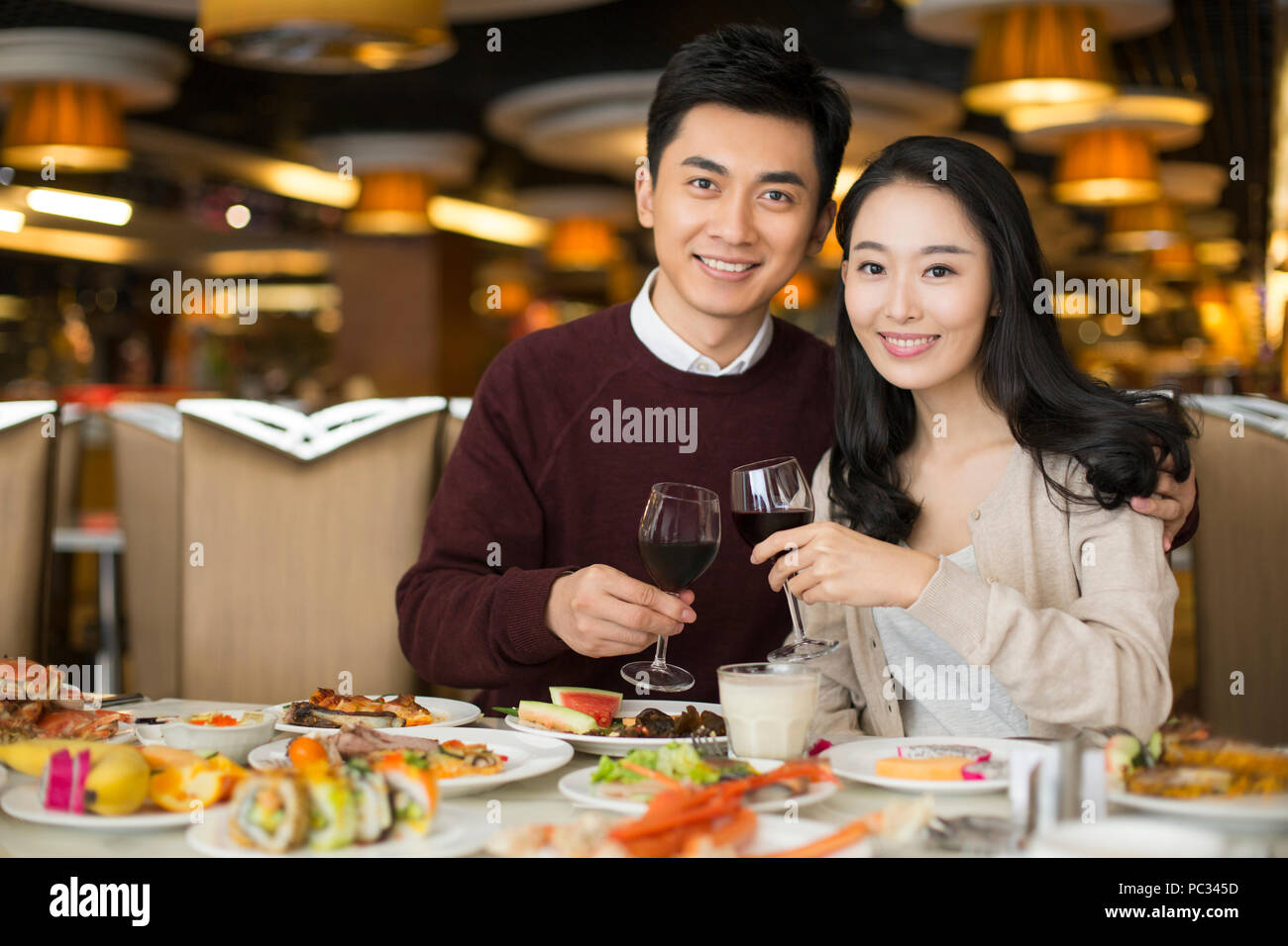 Cheerful young Chinese couple toasting with red wine Stock Photo - Alamy