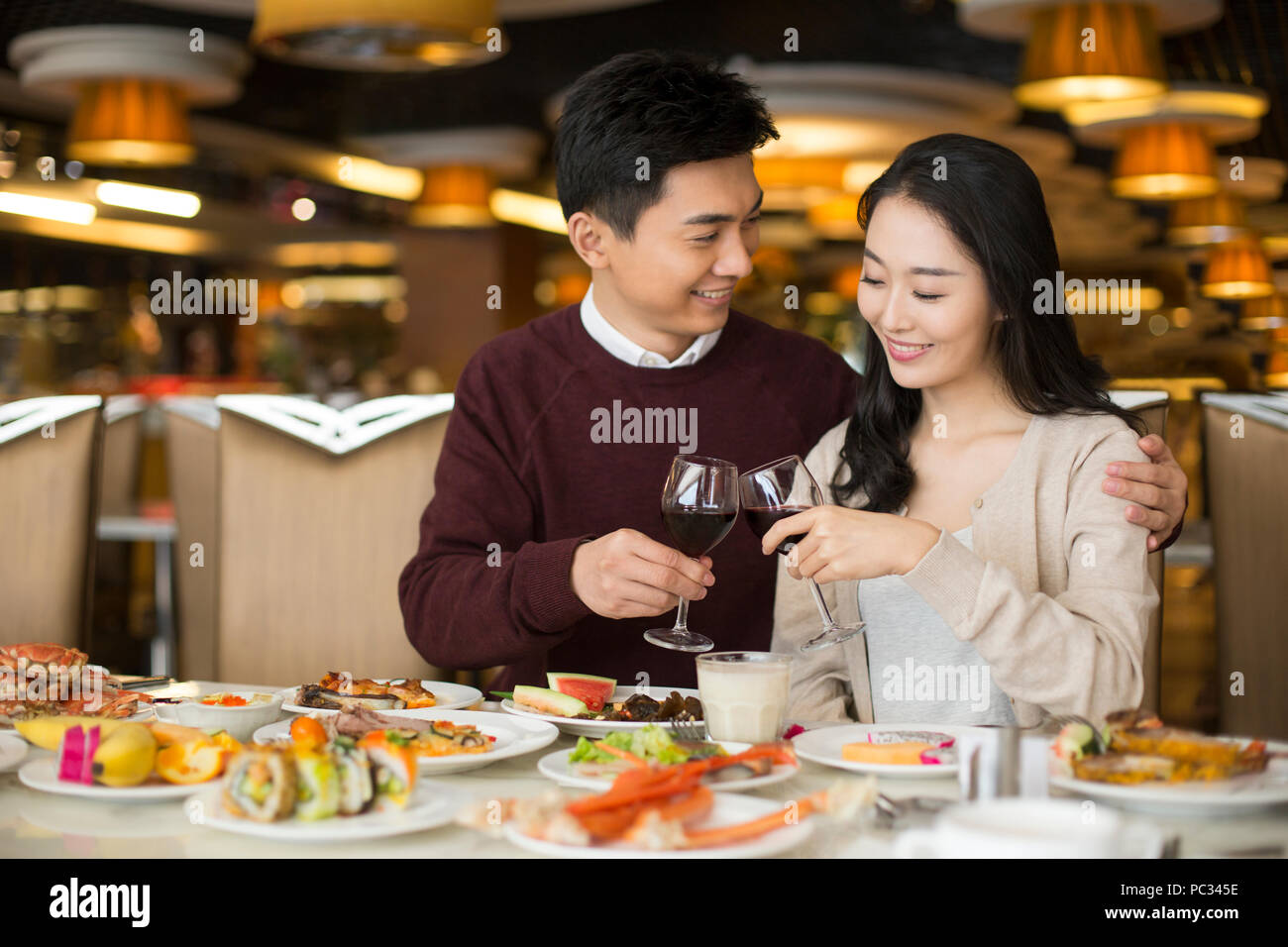 Cheerful young Chinese couple toasting with red wine Stock Photo - Alamy