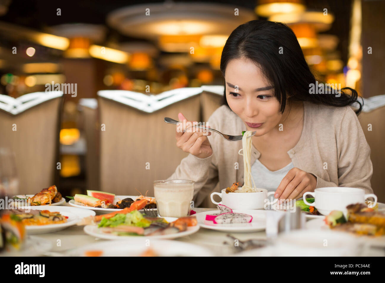 Cheerful young Chinese woman having buffet dinner Stock Photo - Alamy