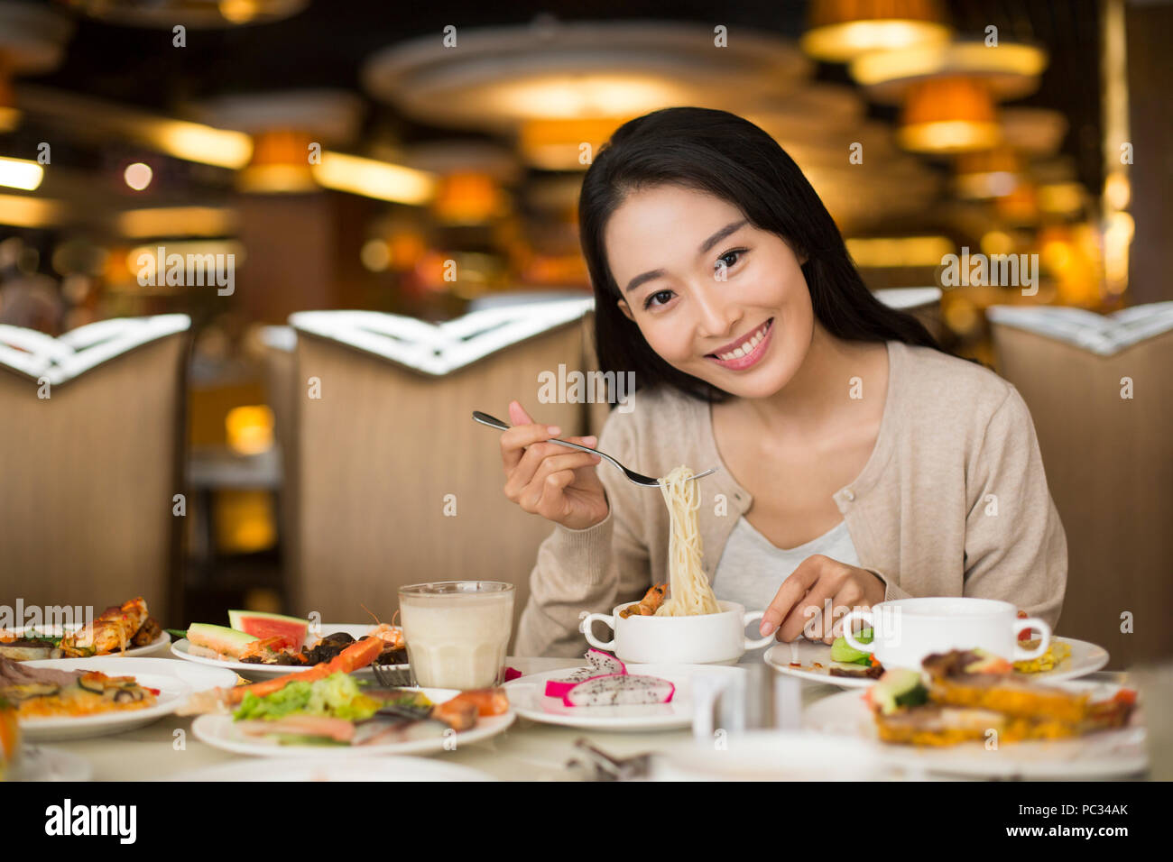 Cheerful young Chinese woman having buffet dinner Stock Photo - Alamy