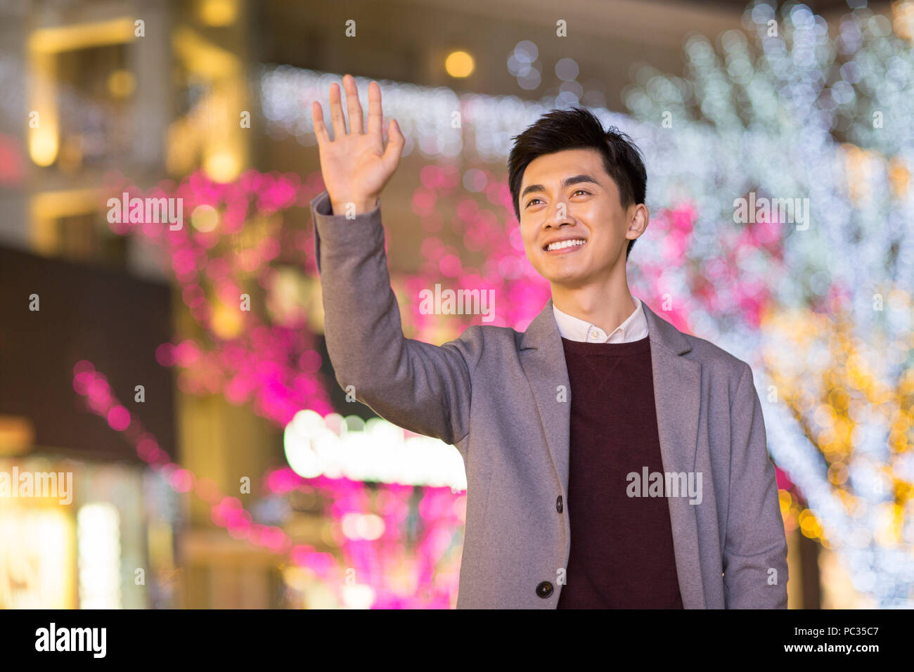 Cheerful young Chinese man waving Stock Photo - Alamy
