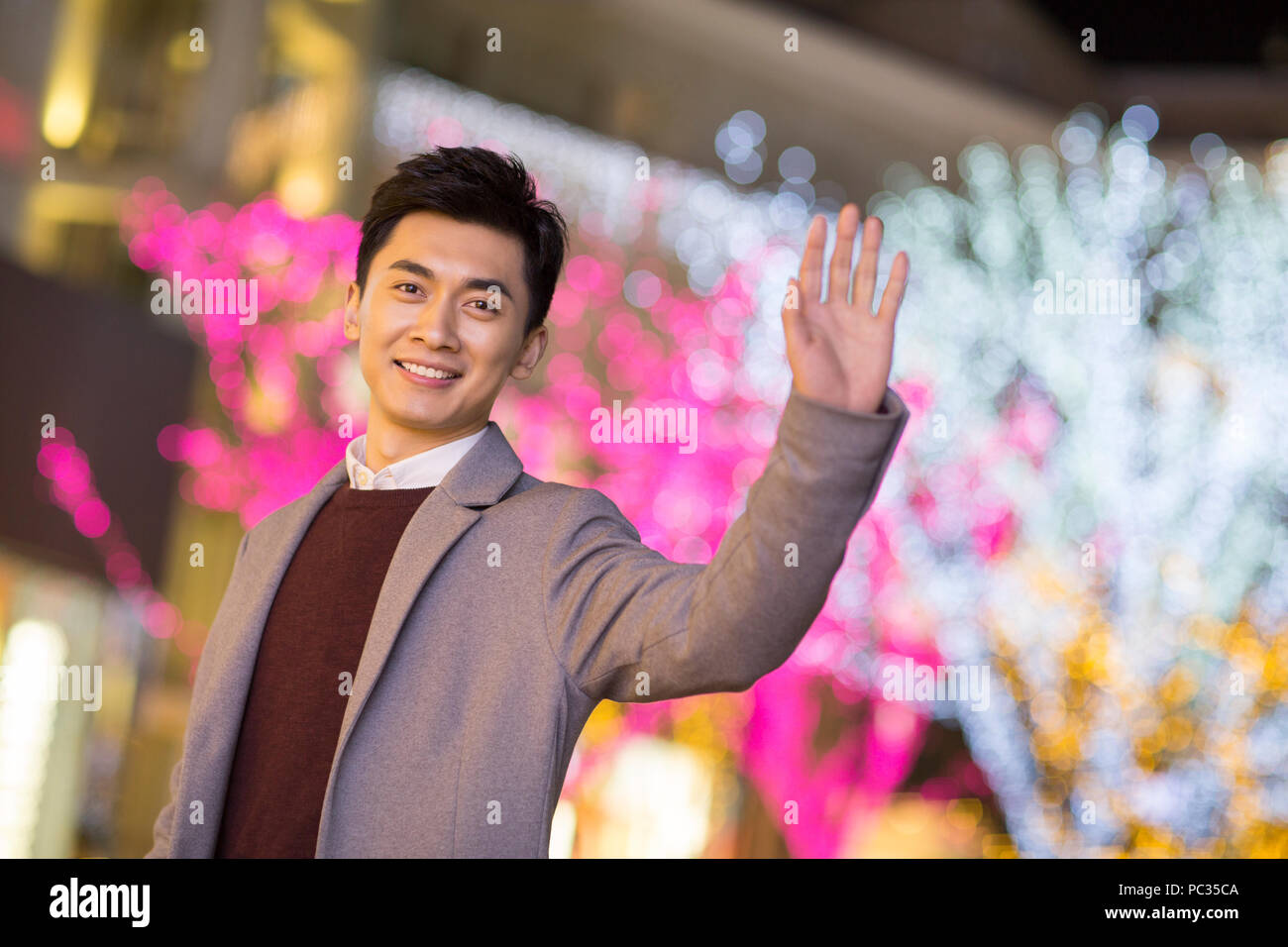 Cheerful young Chinese man waving Stock Photo - Alamy