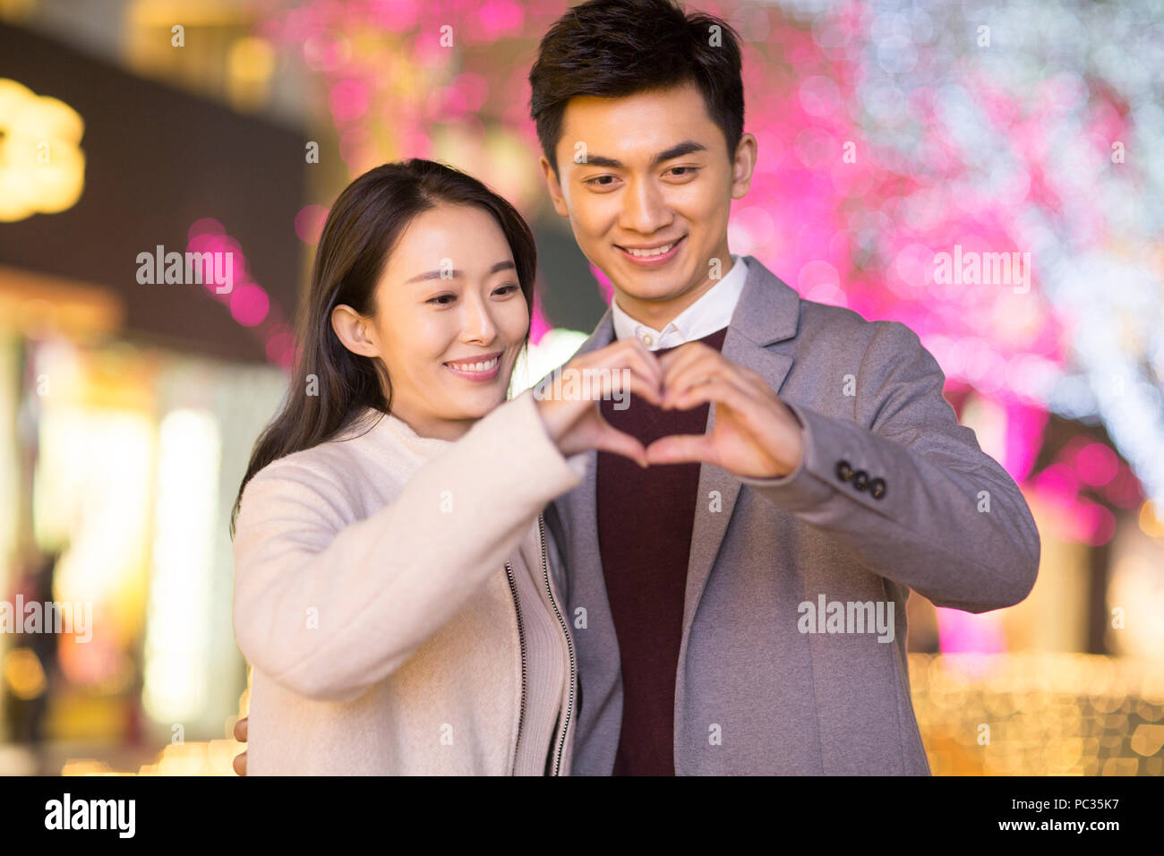 Cheerful young Chinese couple making heart shape with their hands Stock ...