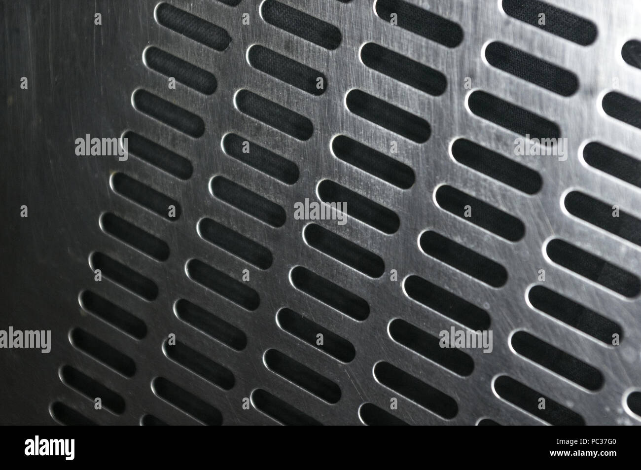 stainless steel grating with oblong holes on black background, close-up ...