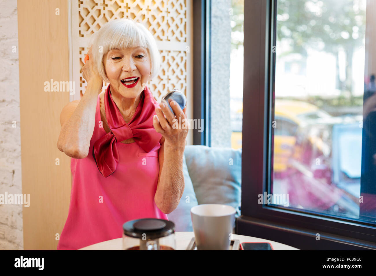 Joyful look. Positive nice woman smiling while looking at herself in ...
