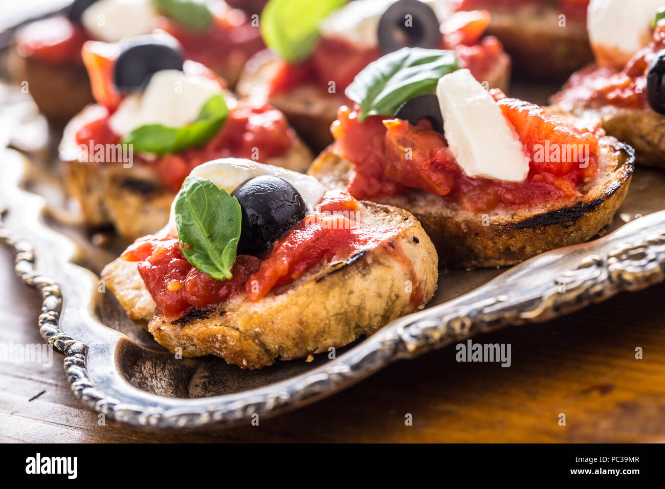 Bruschetta toast with mozzarella tomatoes olives basil and olive oil ...