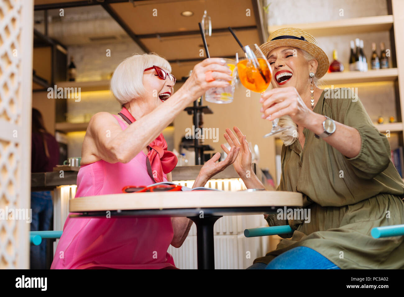 Cheers to us. Positive nice women cheering with cocktails while having ...