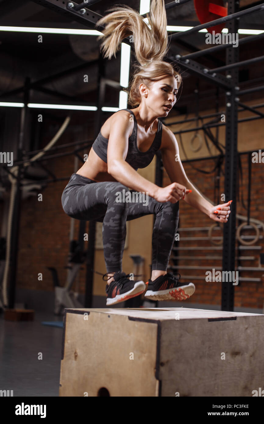 personal trainer is doing cross fit exercise including box jumping ...
