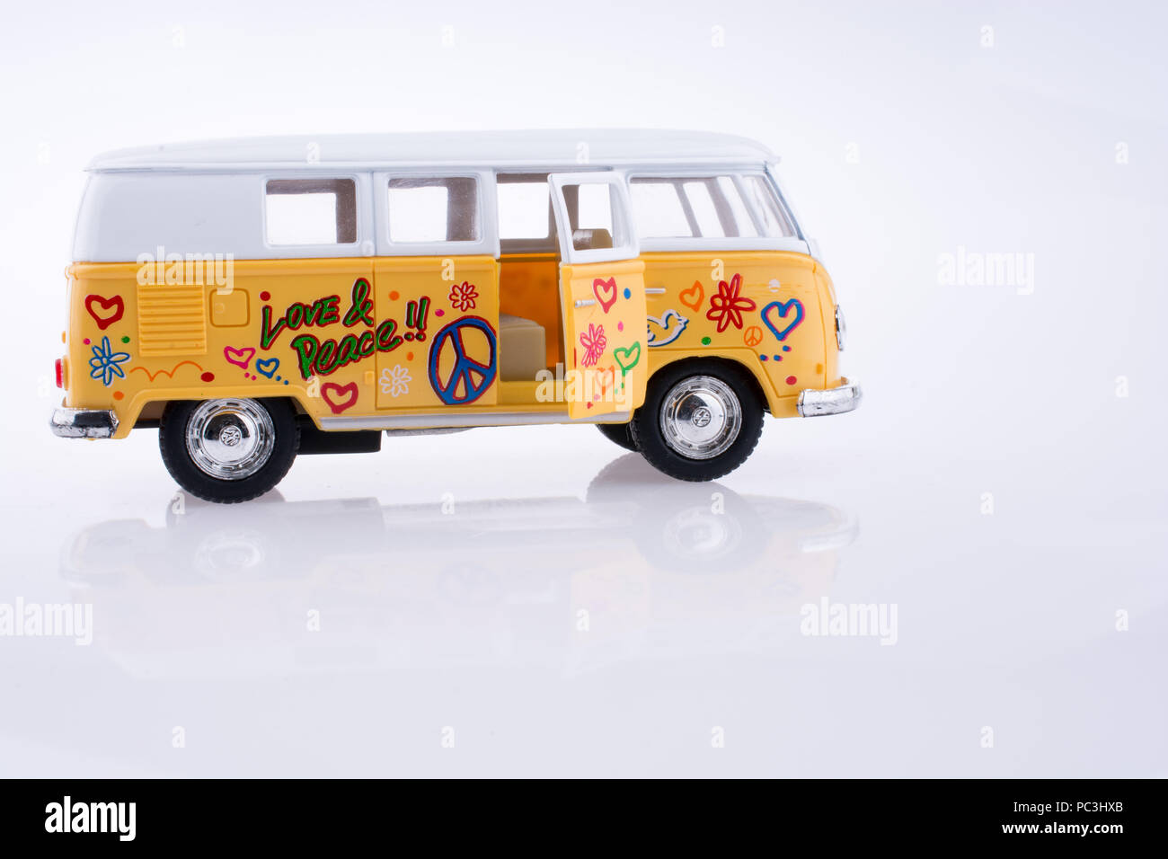 Hand holding a yellow Peace Van on a white background Stock Photo - Alamy