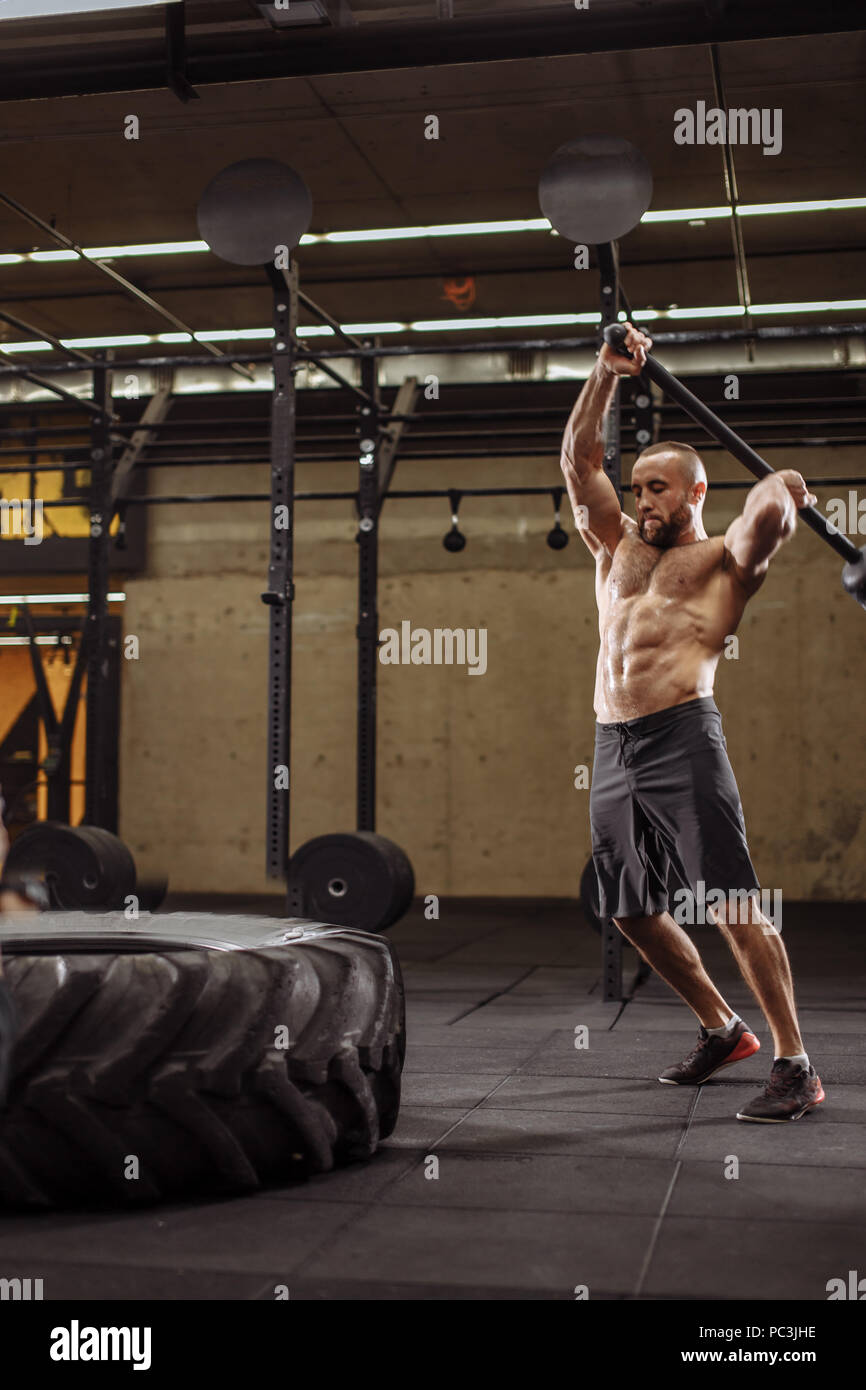 strong bodybuilder ia making great efforts to hit the tractor tire ...