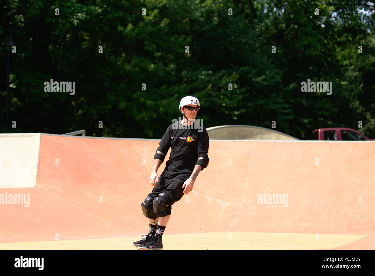 Adult man skateboarding in park with protection gear on Stock Photo - Alamy