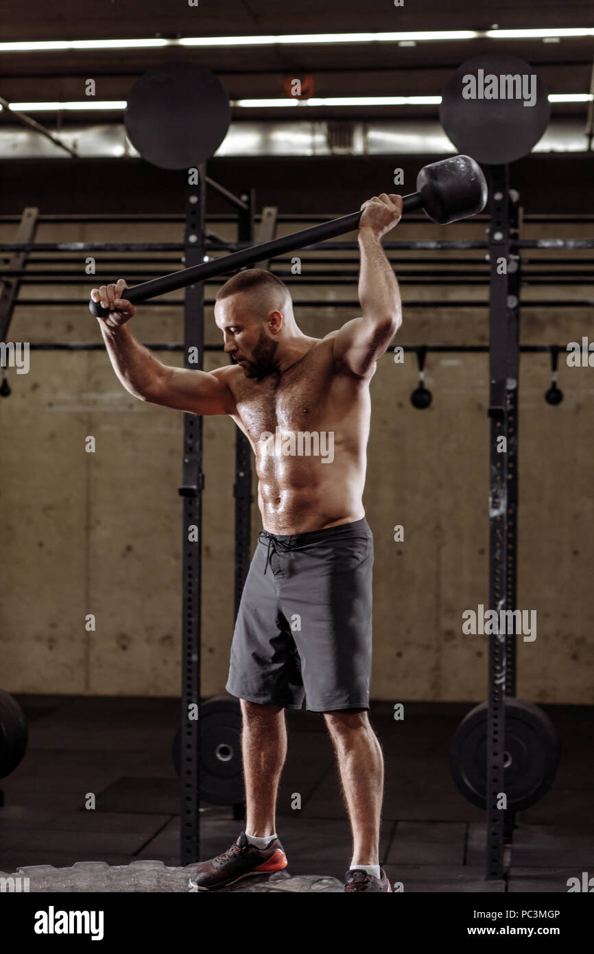 side view shot. attractive man lifting the hammer overhead. full length ...