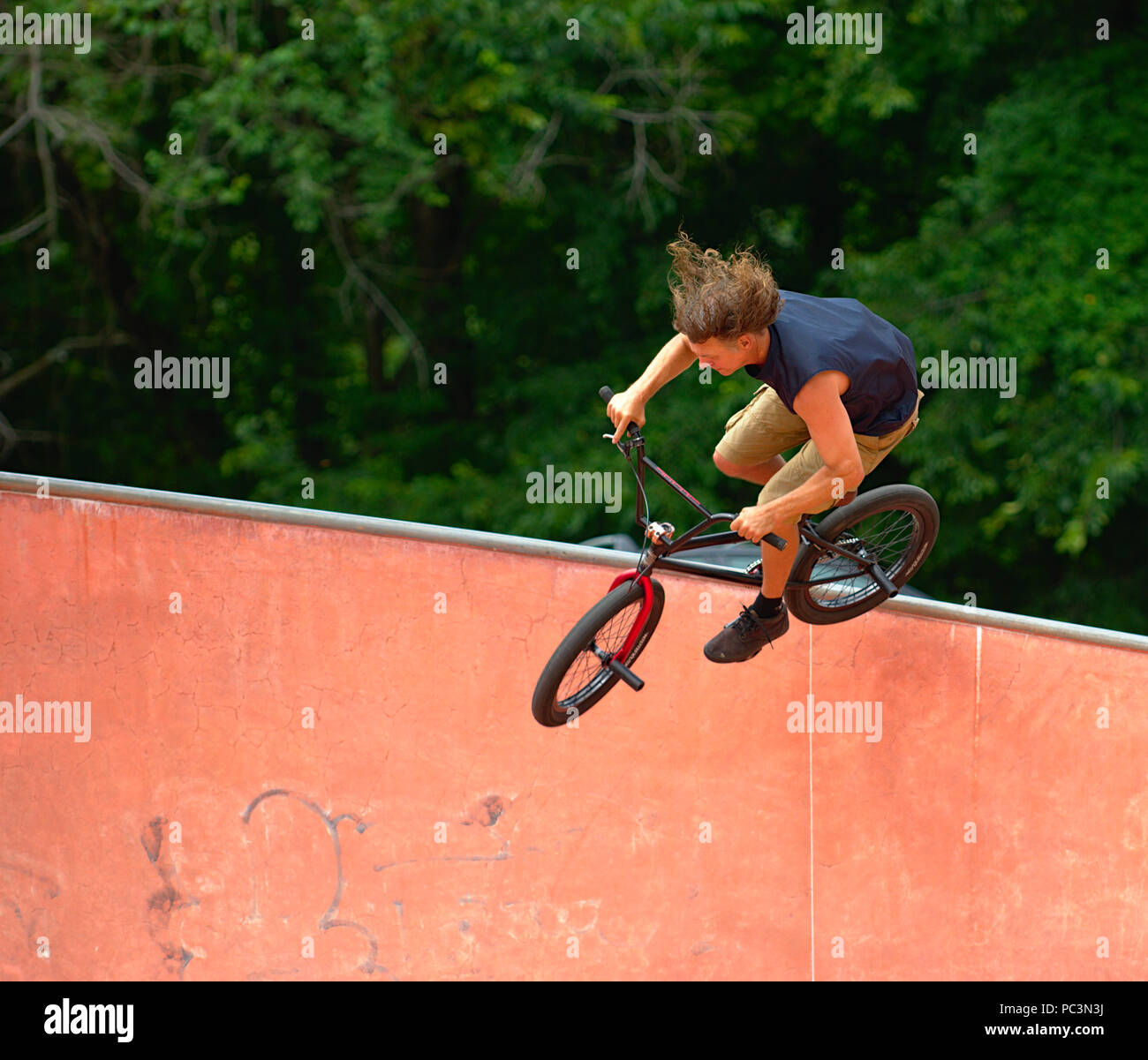 Adult male doing bike tricks a park Stock Photo - Alamy