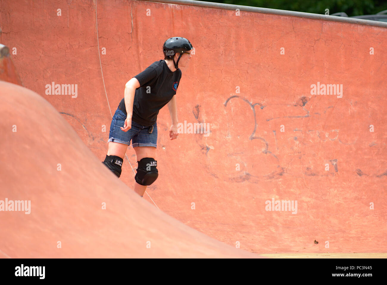 Adult female skateboarding at park with protection gear on Stock Photo ...