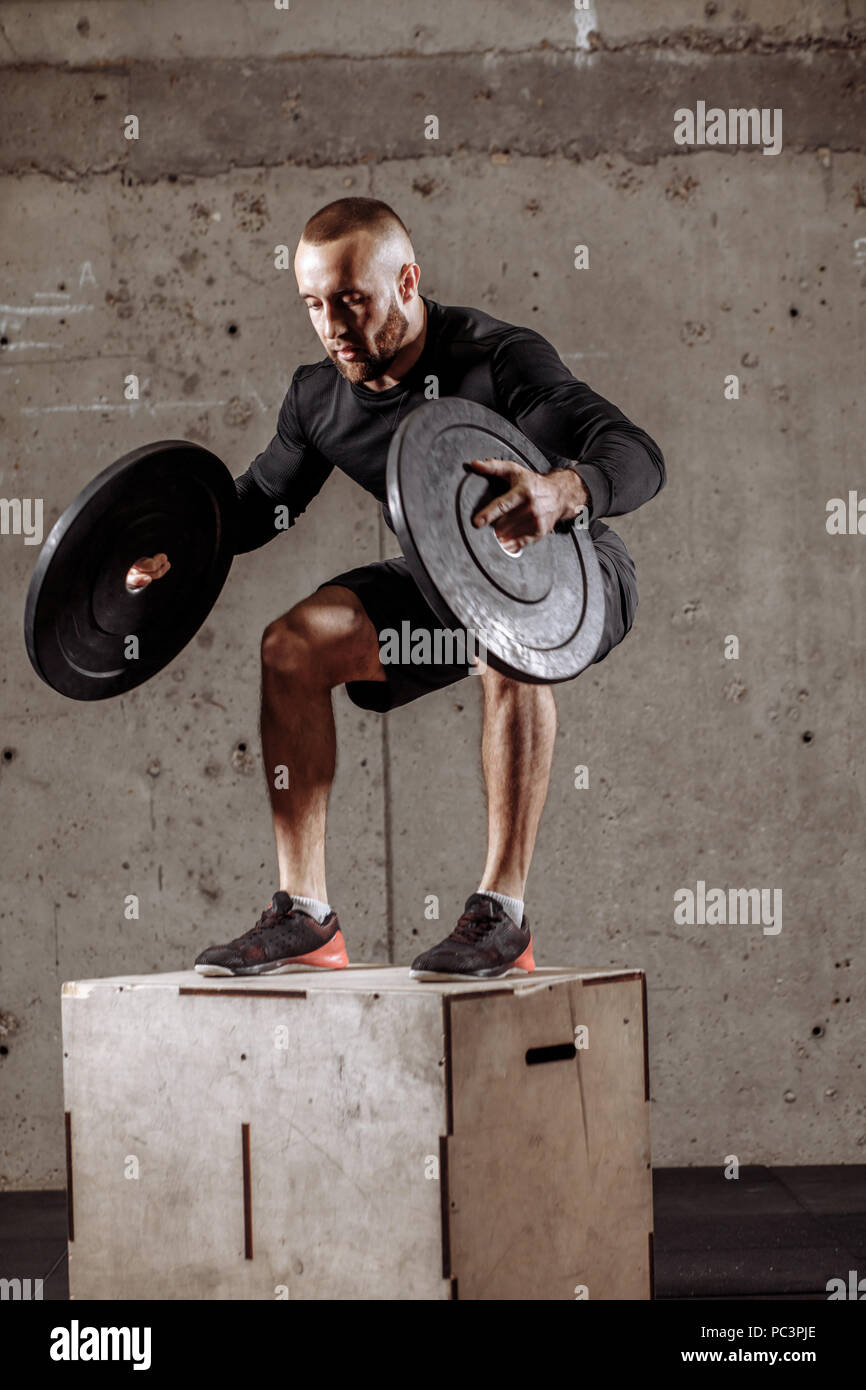 talented bodybuilder is showing the movements with weight tire. side ...