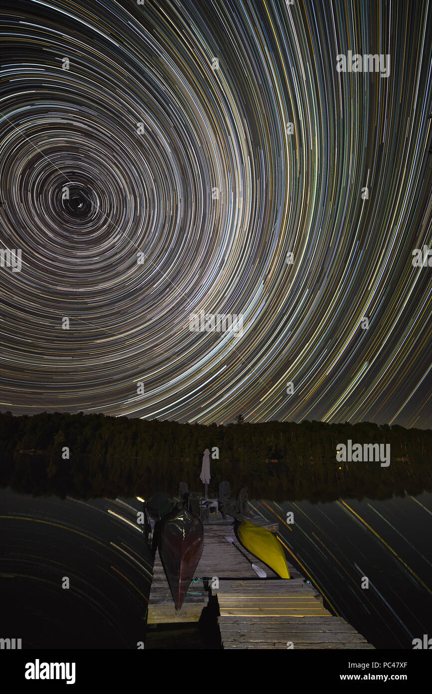 Star Trails in the night sky over a cottage dock on a lake - Ontario ...