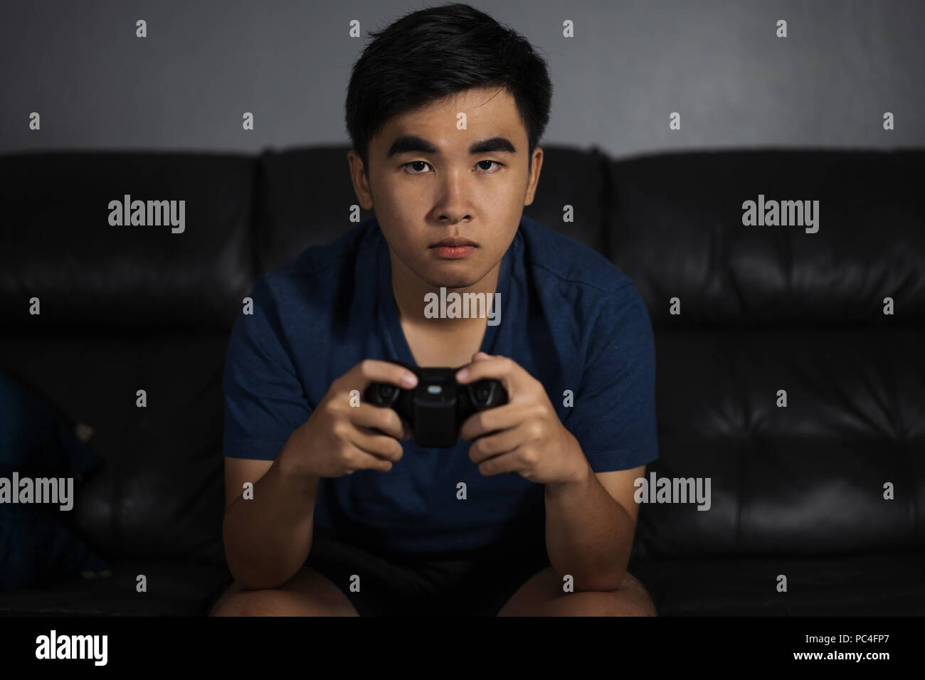 young man playing video game with joystick in the living room at night ...