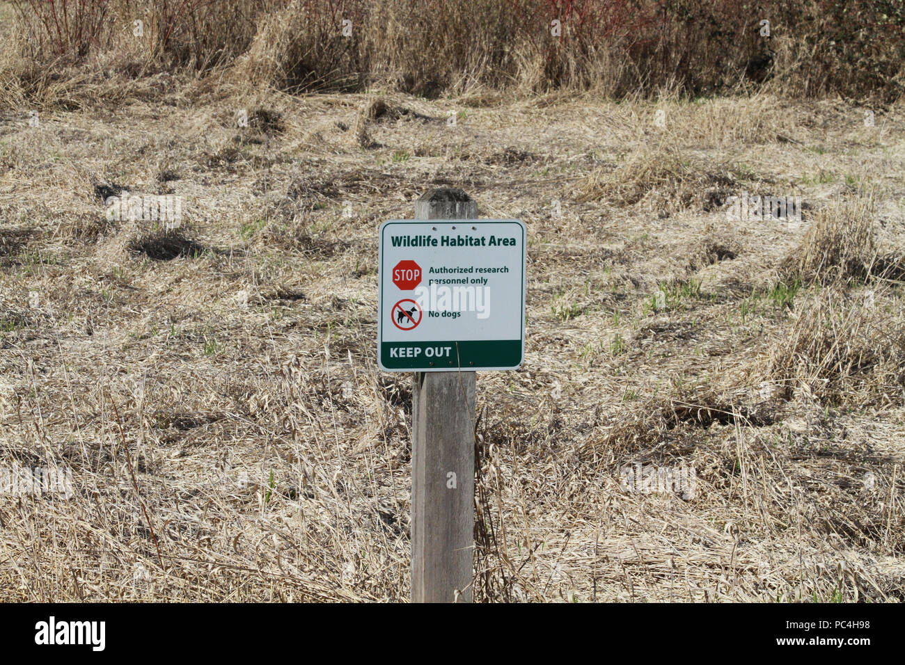 A sign in the middle of a meadow indicating a habitat wildlife area ...