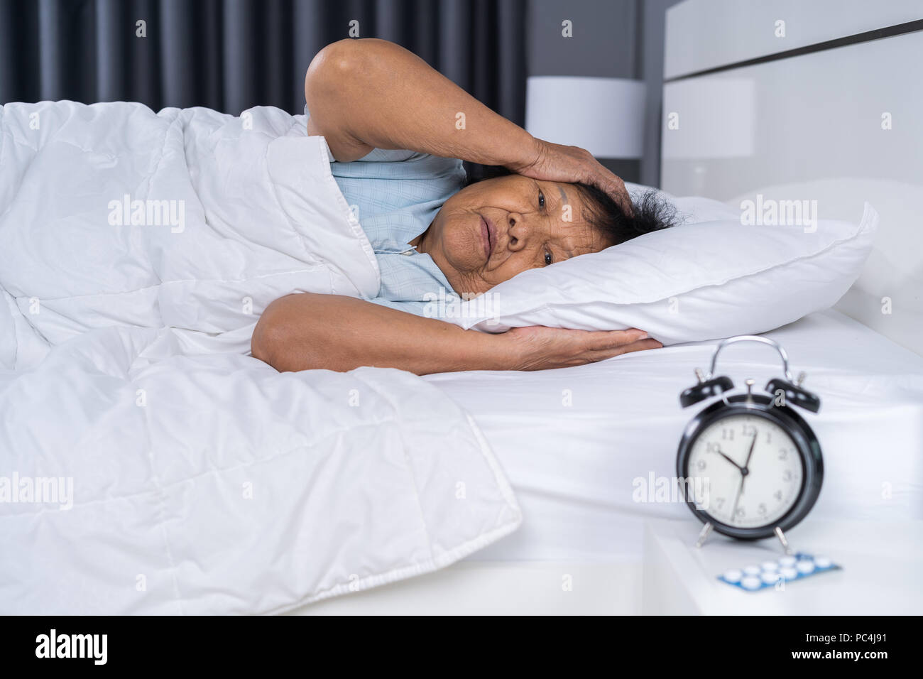 Old woman suffering from insomnia is trying to sleep in bed at night ...