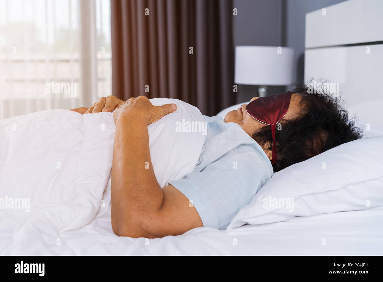 senior woman with eye mask sleeping on a bed in bedroom Stock Photo - Alamy
