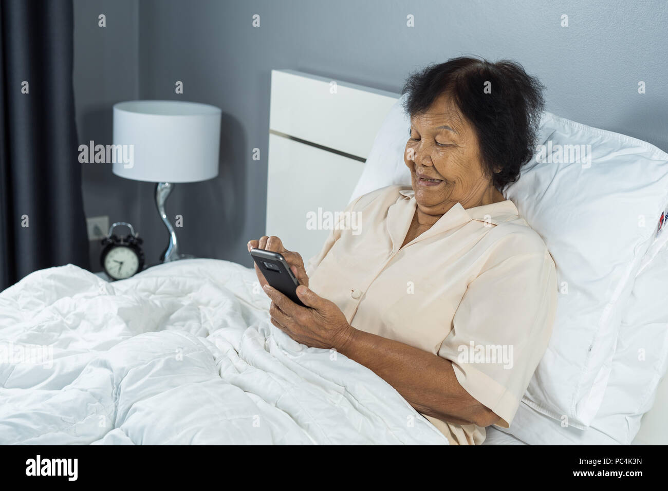 senior woman using mobile phone on a bed Stock Photo - Alamy