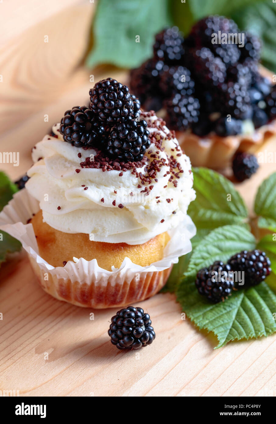 Tasty blackberry cakes with berries and cream on a wooden table Stock ...