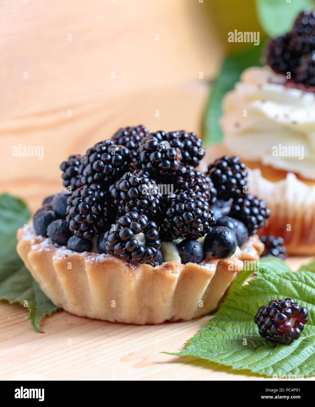Tasty blackberry cakes with berries and cream on a wooden table Stock ...
