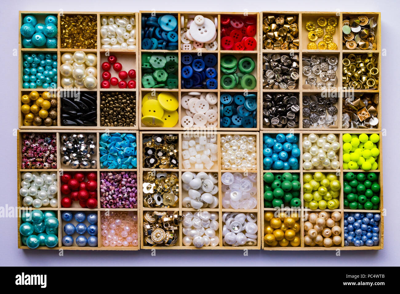 Clothes buttons in wooden boxes on white fabric background. Photo from ...