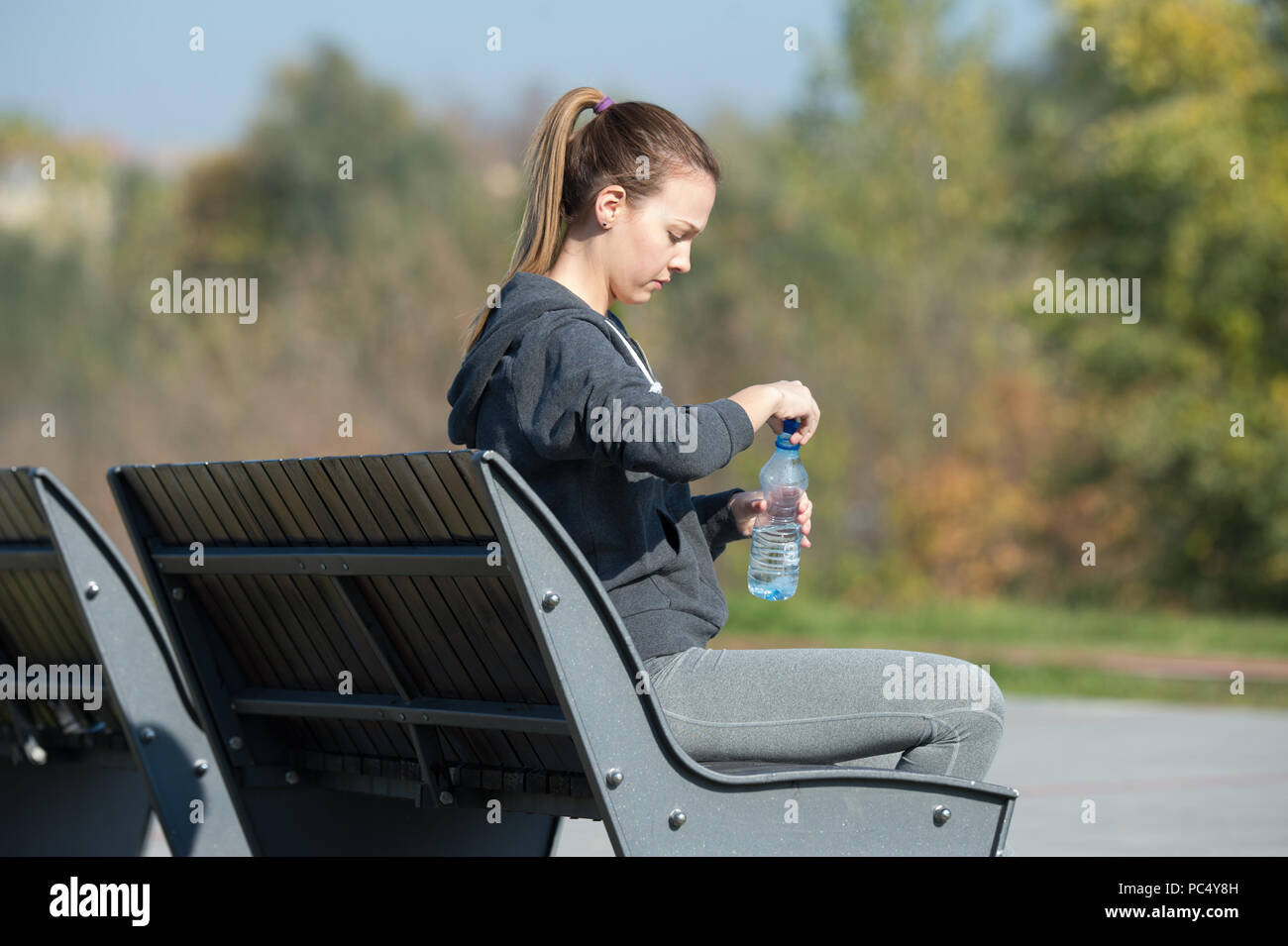 Girl sitting on a park bench after running Stock Photo - Alamy