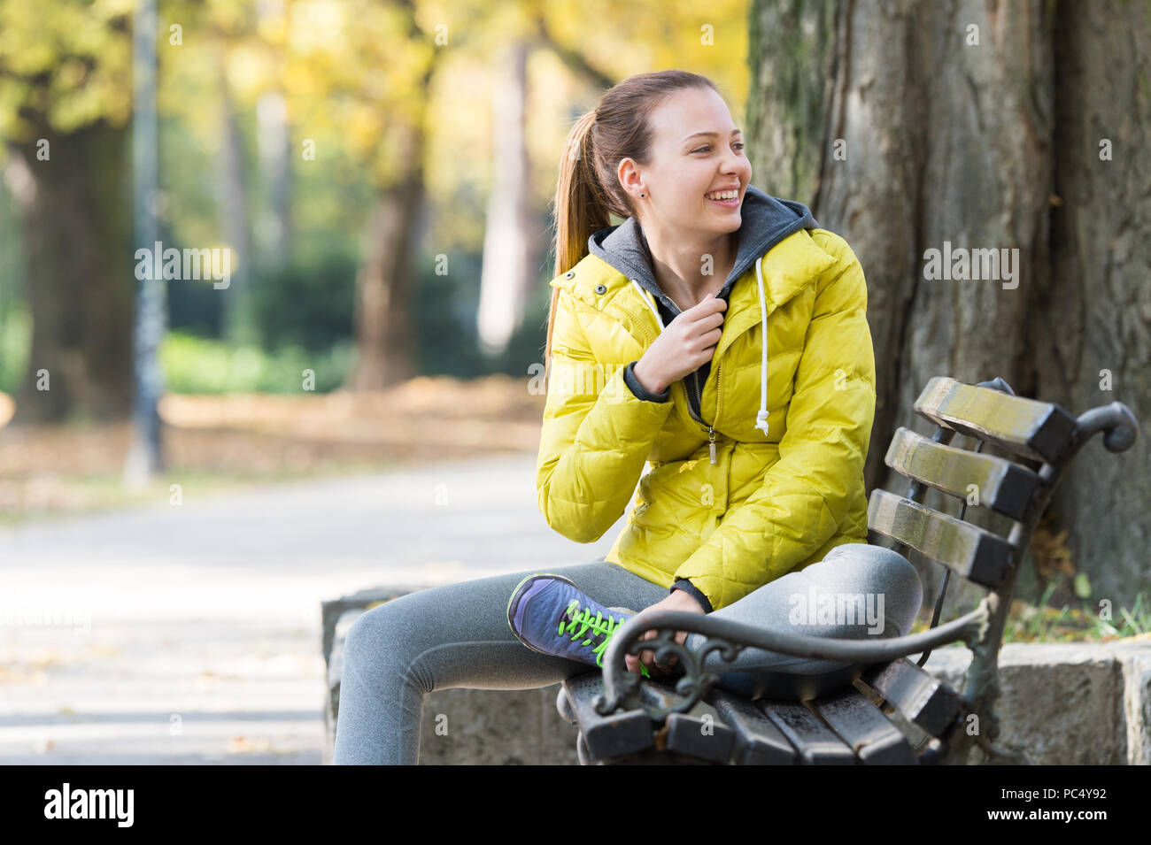 Girl sitting on a park bench after running Stock Photo - Alamy