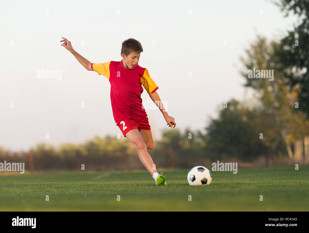 kid kicking a soccer ball on the field Stock Photo - Alamy