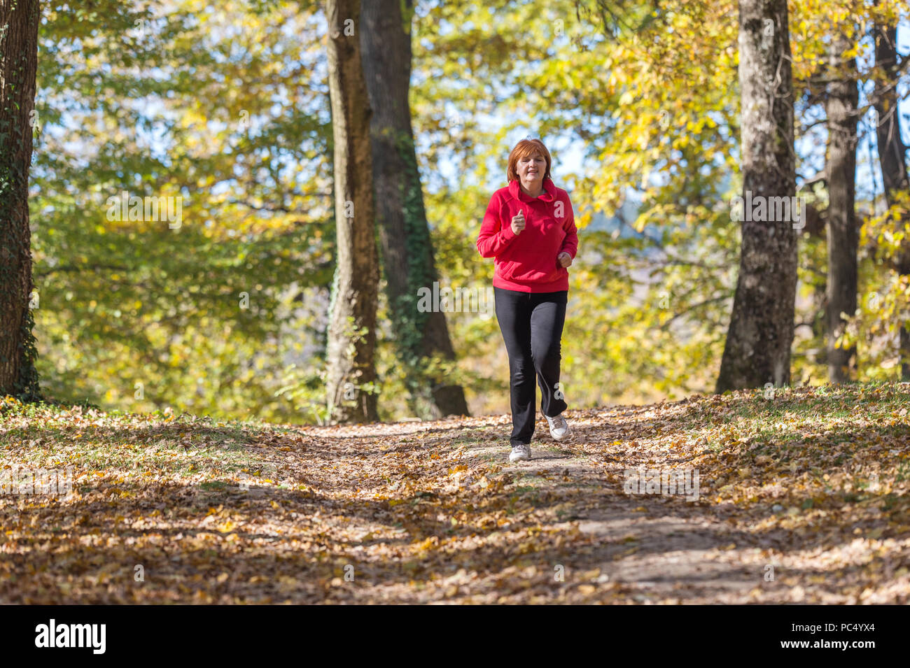 Woman running in autumn park Stock Photo - Alamy
