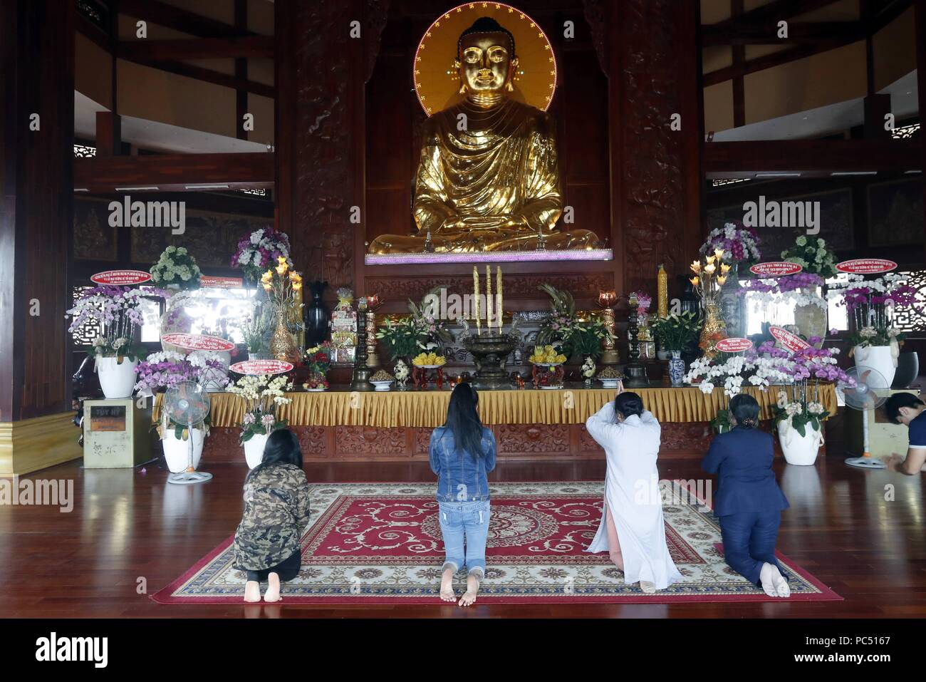 Minh Dang Quang buddhist temple. Golden Buddha statue. Women praying at ...