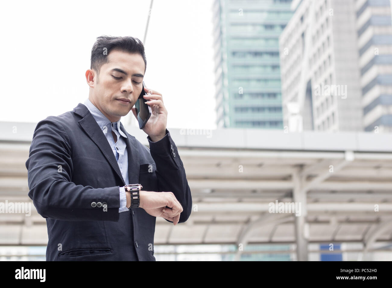 businessman standing on walkway of building and looking on watch to ...