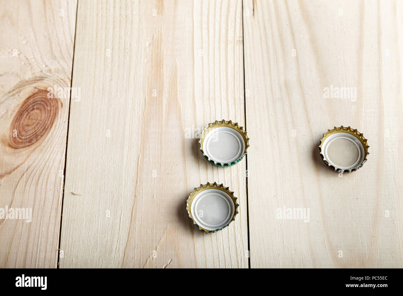 three caps from beer on a wooden board, top view Stock Photo - Alamy