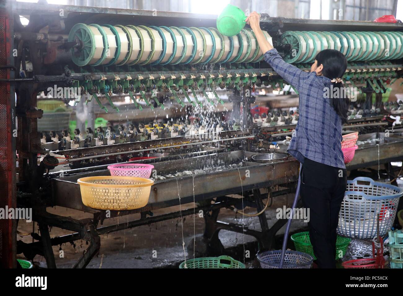 Traditional silk factory. Woman working on silk spinning machine. Dalat ...