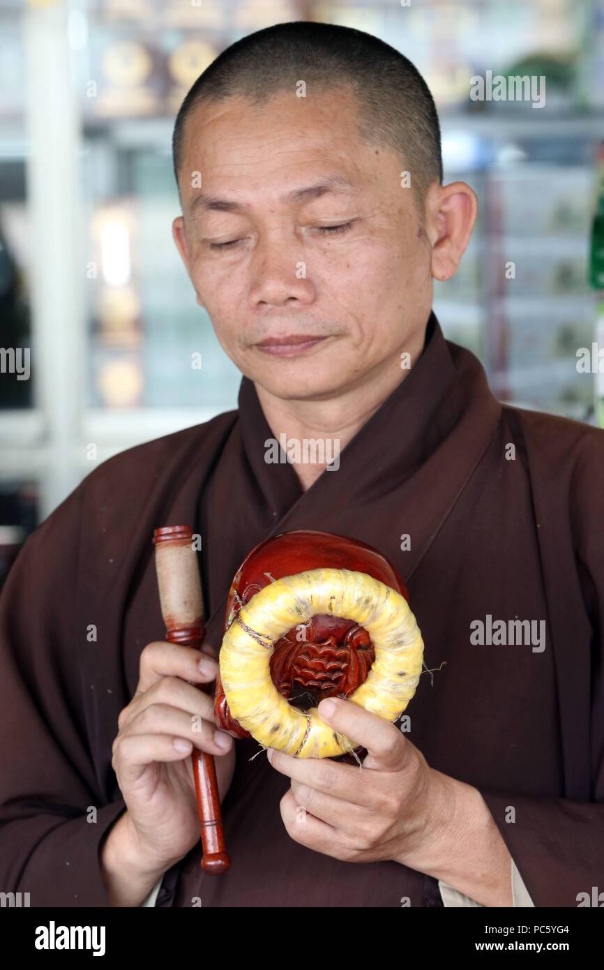 Buddhist ceremony. Monk playing on a wooden fish (percussion instrument ...