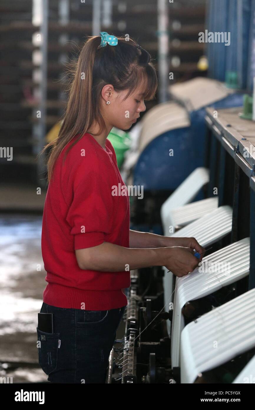 Traditional silk factory. Woman working on silk spinning machine. Dalat ...