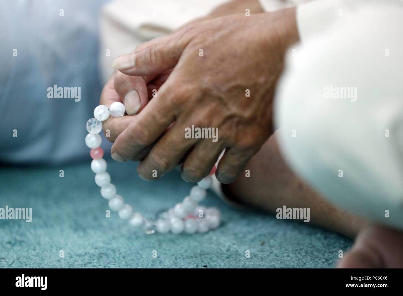 Masjid Al Rahim Mosque. Man praying in a mosque with Tasbih (prayer ...